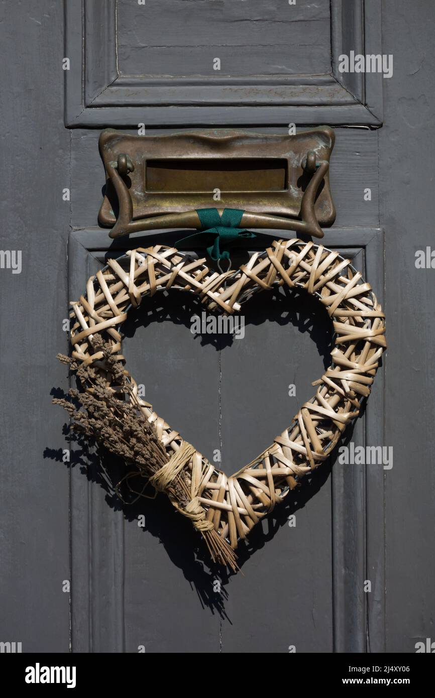 Love heart shaped wicker wreath door decoration on a dark grey painted ...