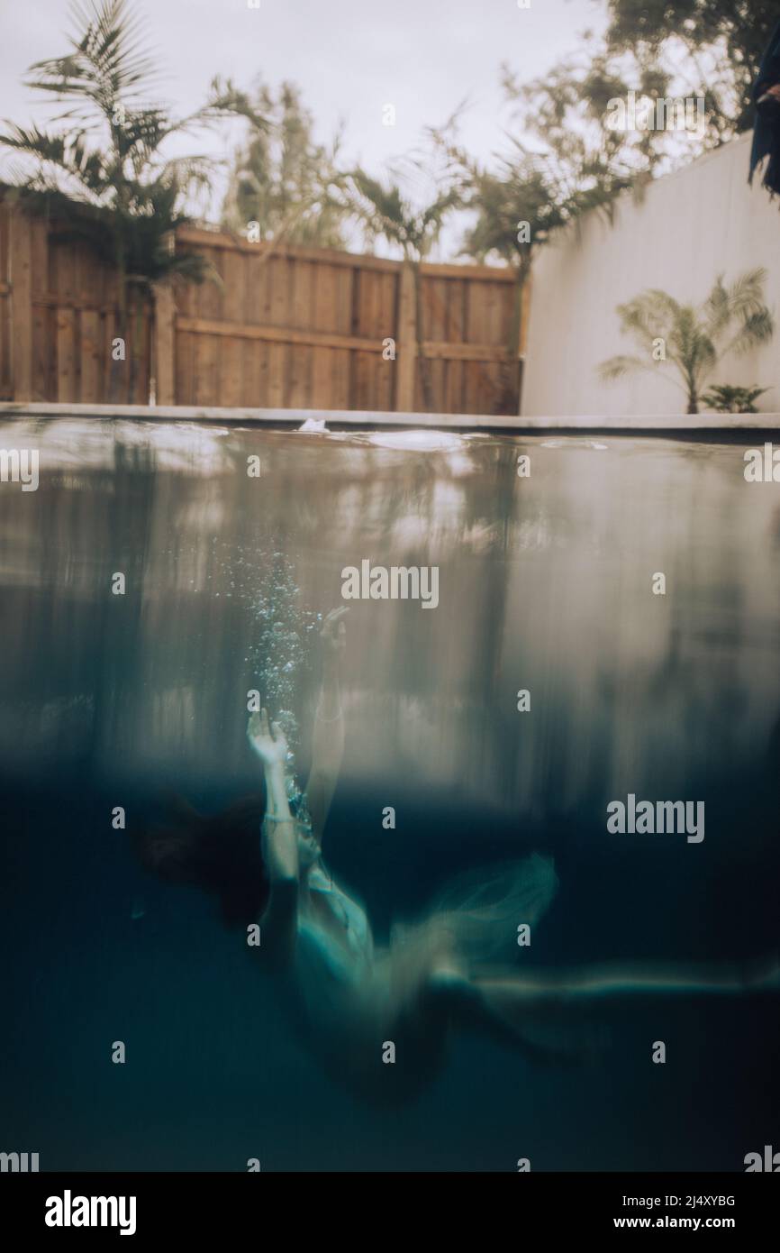 A woman sinking in a pool under glassy water Stock Photo - Alamy