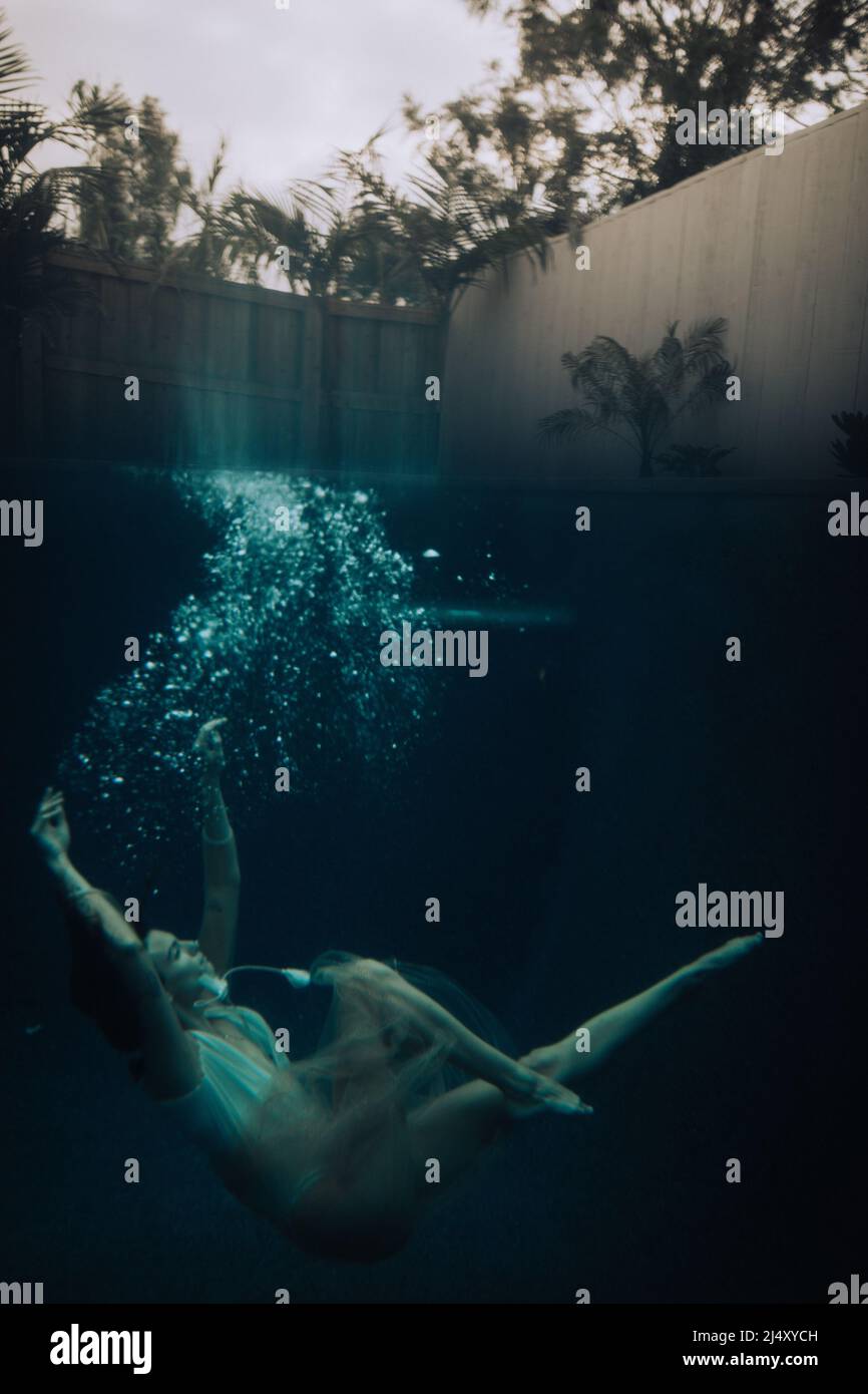 Woman dancer falling through deep dark blue water Stock Photo - Alamy