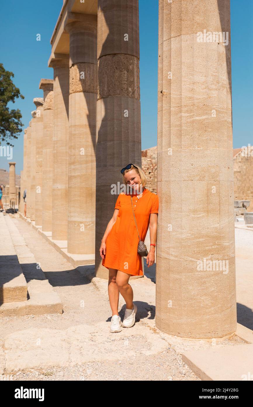 A woman stands in the ancient acropolis of Lindos against the ...
