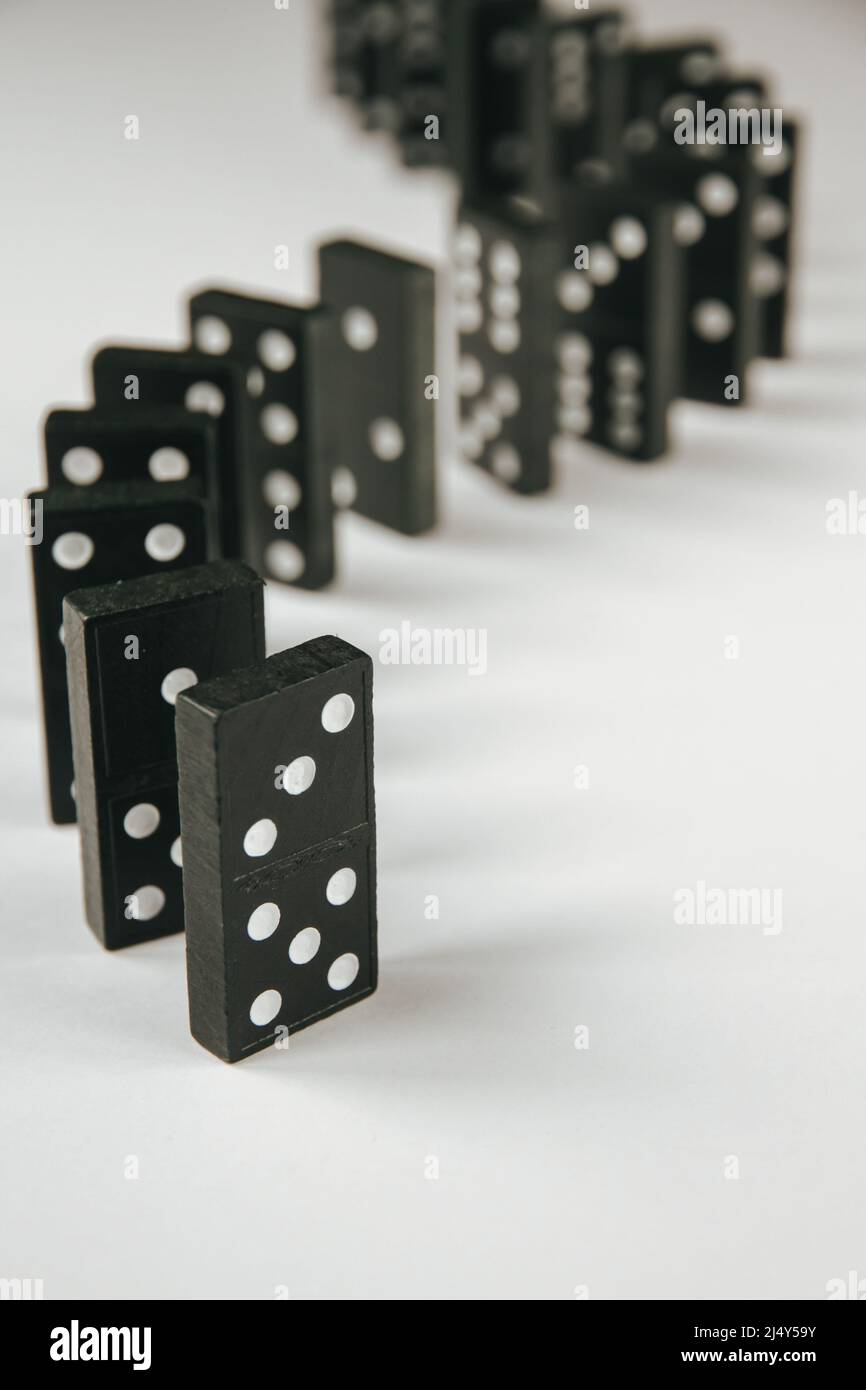 Black dominoes chain on a white table background. Domino effect concept ...