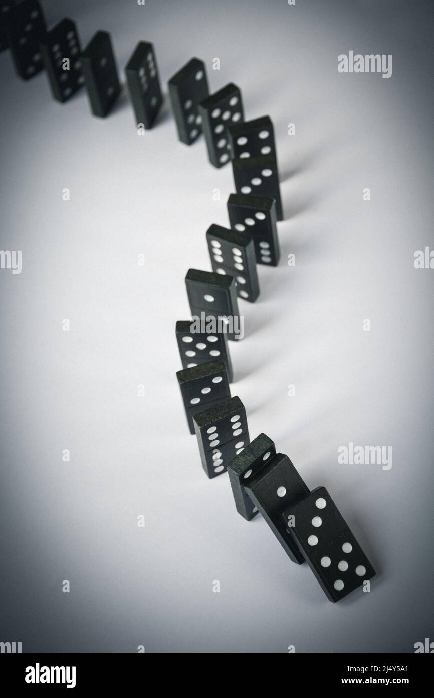 Black dominoes chain on a white table background. Domino effect concept ...