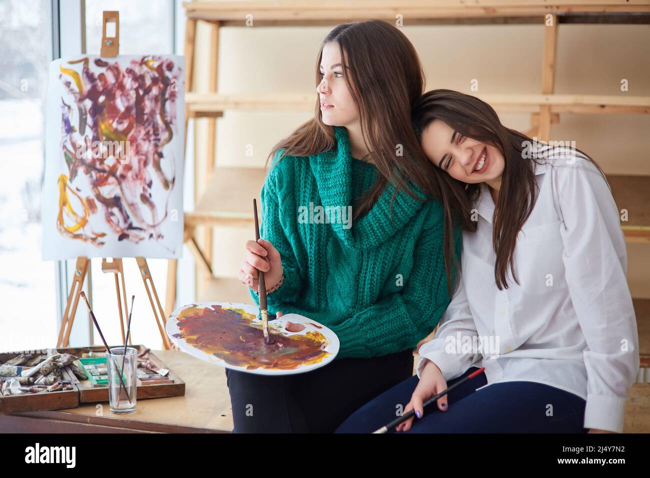 Two young girls, brunettes paint an oil painting in an art workshop ...
