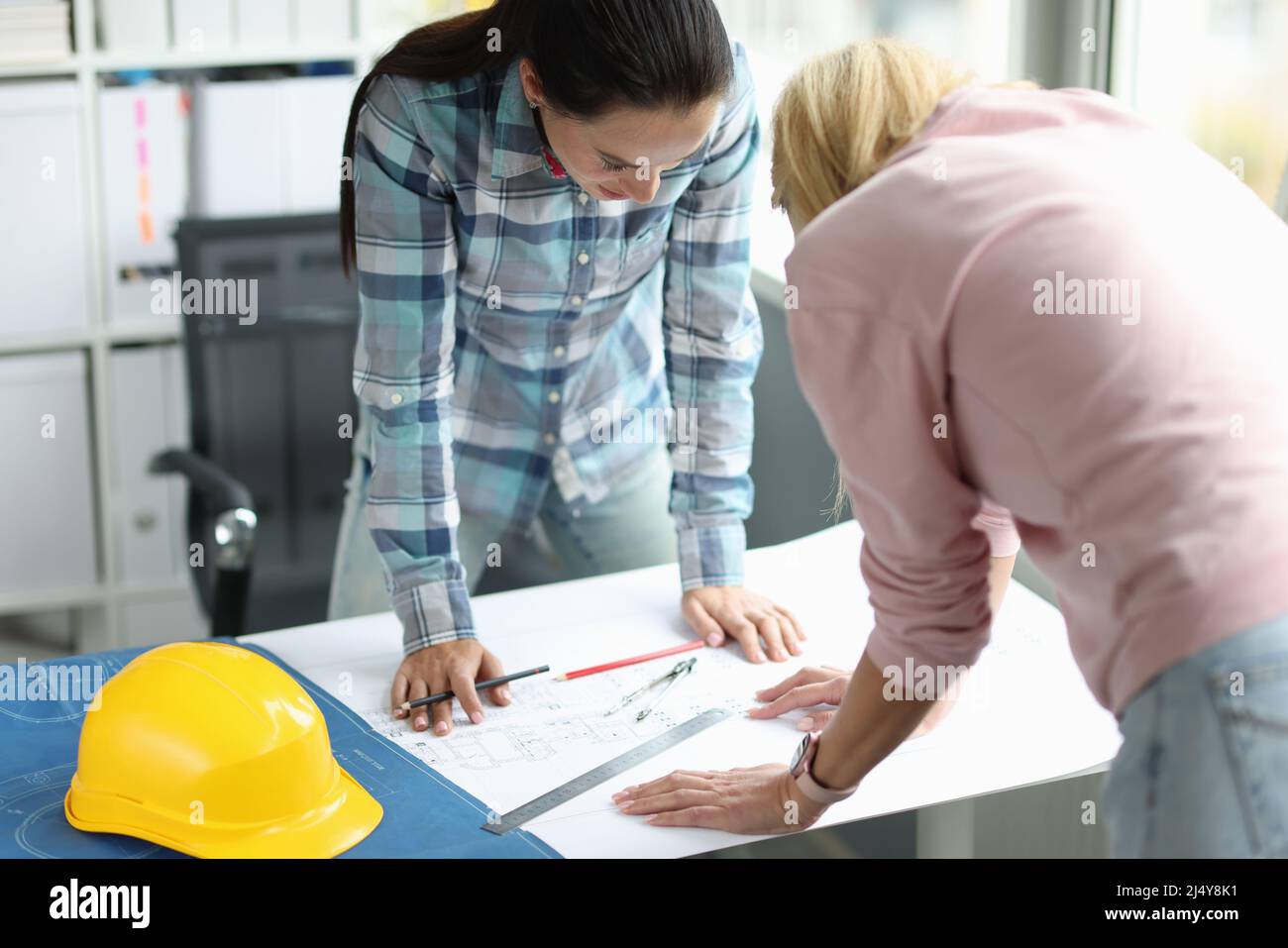 Two female architects are studying blueprint of building house Stock ...