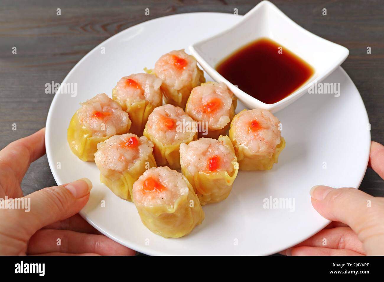 Hand Placing a Plate of Shrimp and Pork Filled Chinese Steamed ...