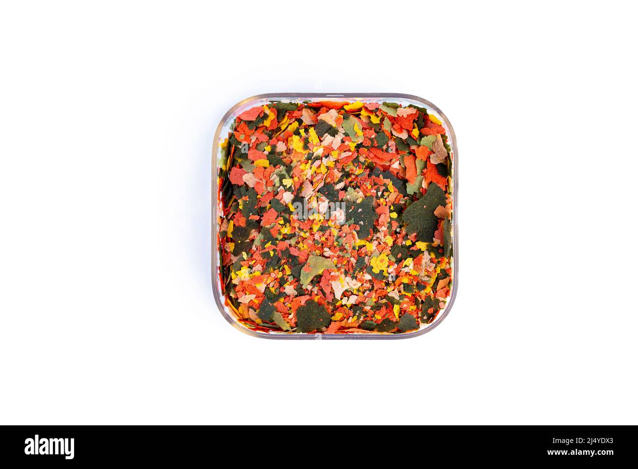 Dry red compound fish feed flakes in a transparent box on White ...