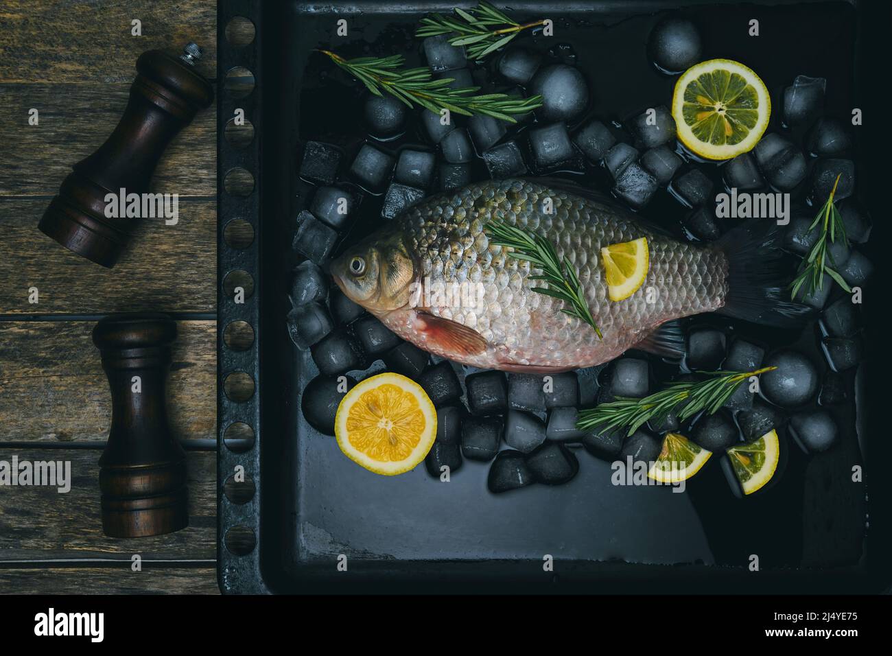 Cooking fish, raw fish on a baking sheet with ice cubes, lemon slices ...