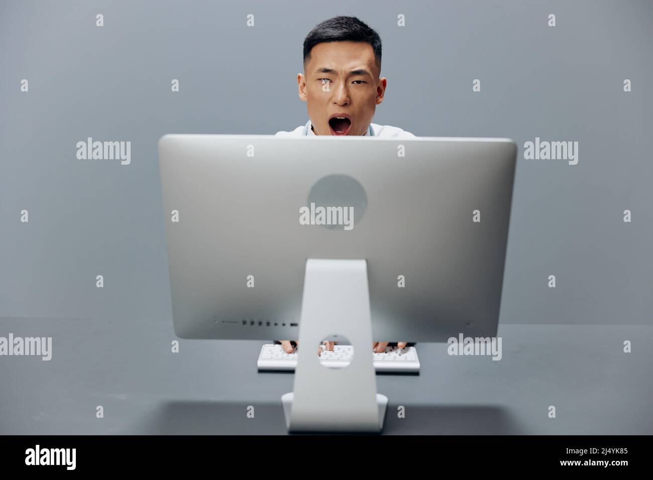 worker working in front of computer sitting at a table in the office ...