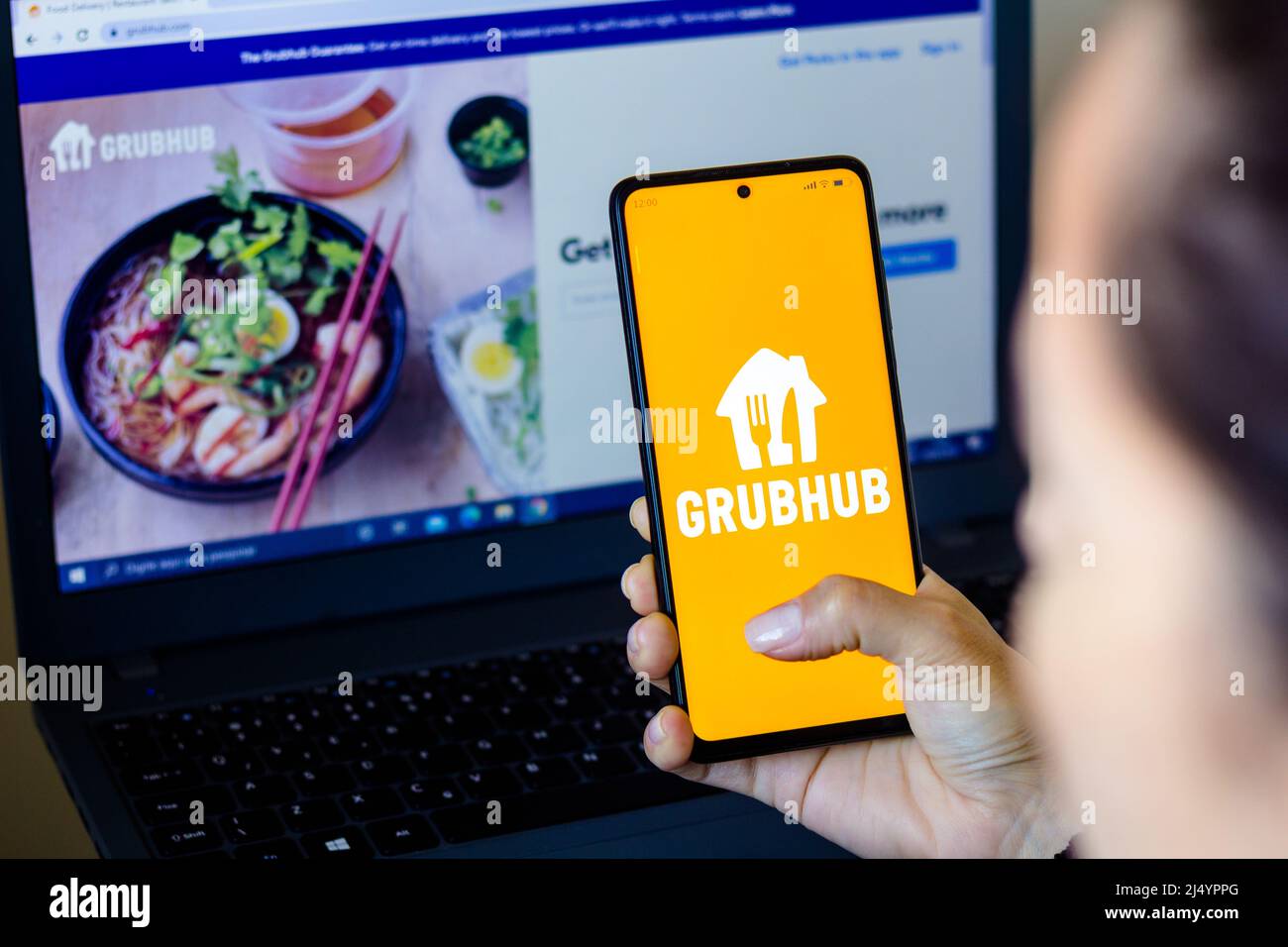 In this photo illustration, a woman holds a smartphone with the Grubhub ...