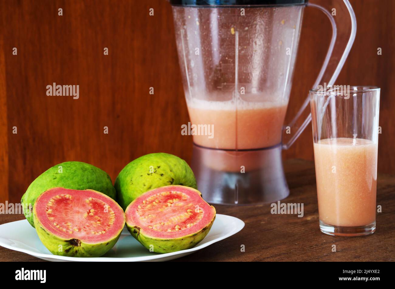 Two whole and halved guavas inside a plate and pitcher and glass with guava juice Stock Photo ...