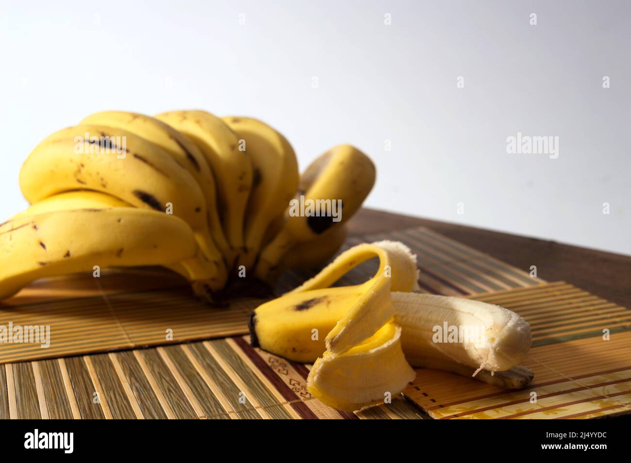 Piece of peeled banana and bunch of banana in the background Stock ...