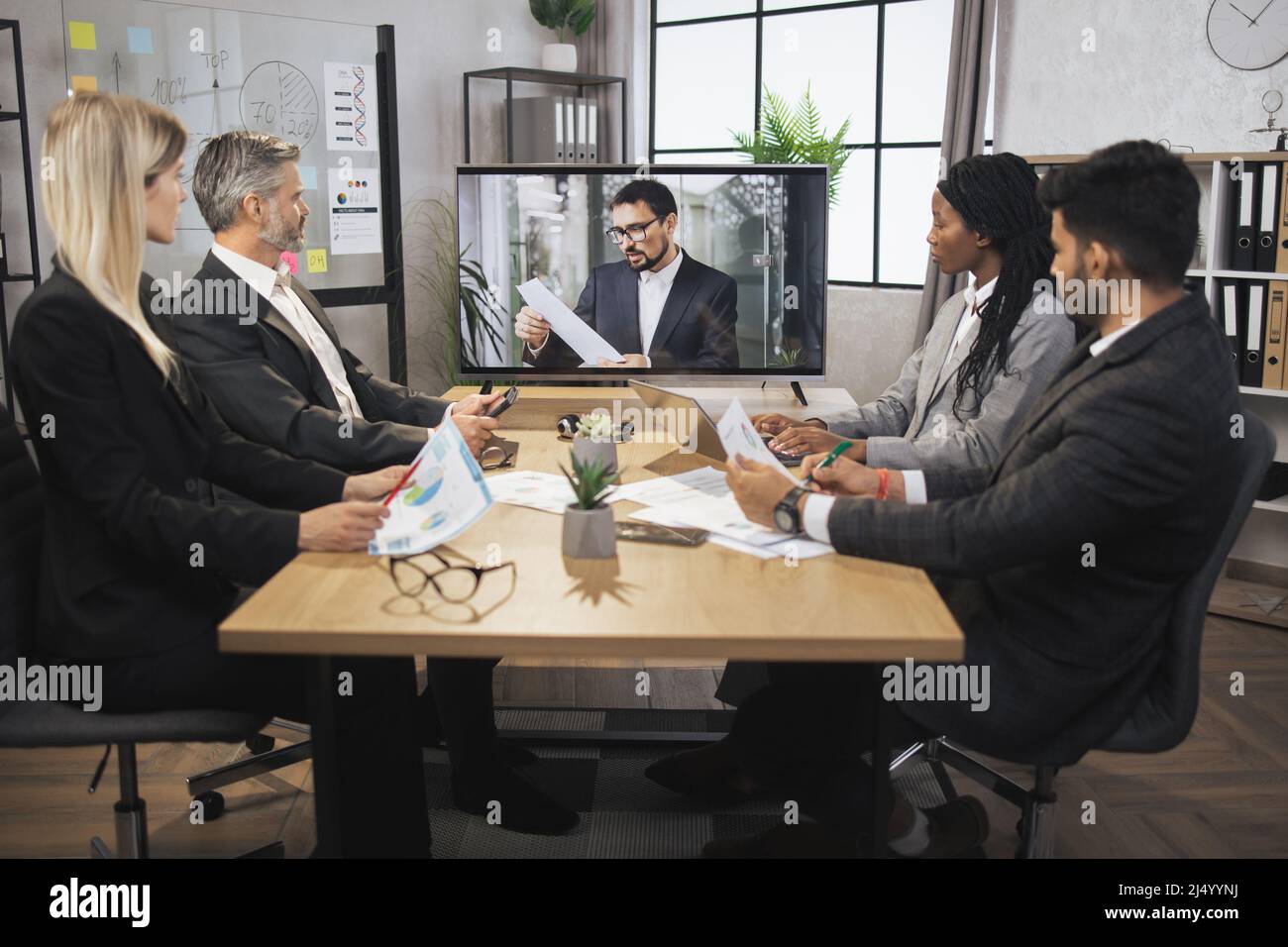 Team of four focused multiethnical businesspeople looking at screen ...
