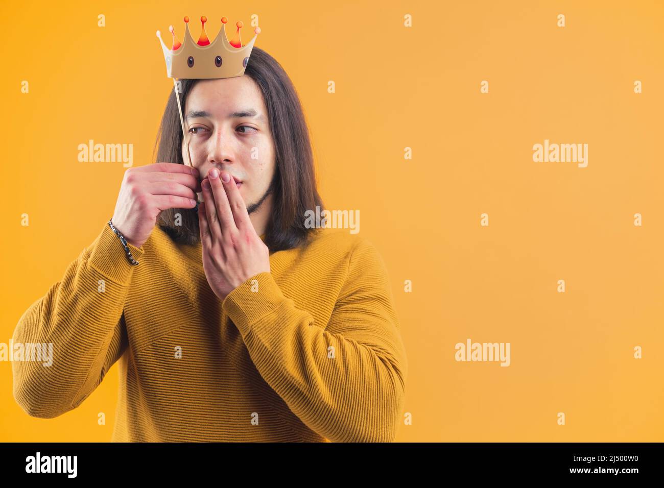 Attractive young man holding paper crown above his head and touching ...