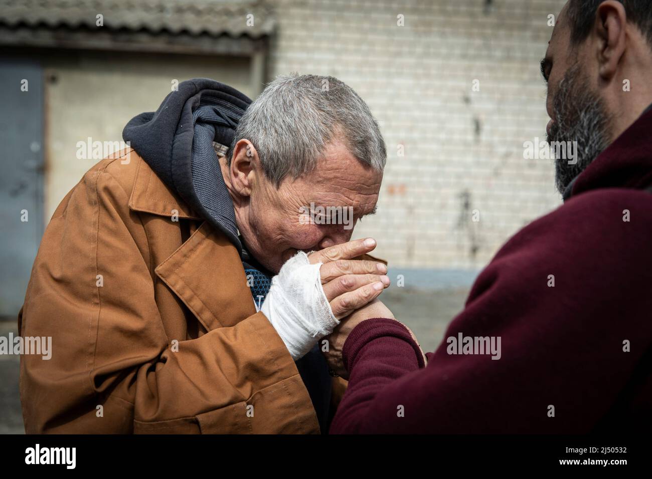 A volunteer helps a man who lost his left arm and thumb of his right ...