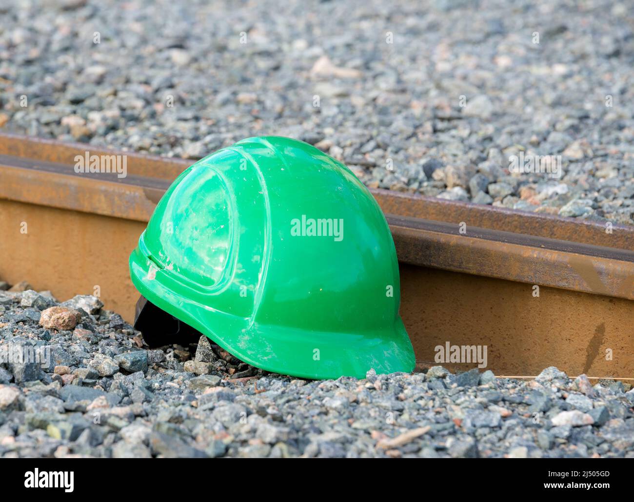 A green hard hat abandoned by a rusty railroad track. Only one of the ...