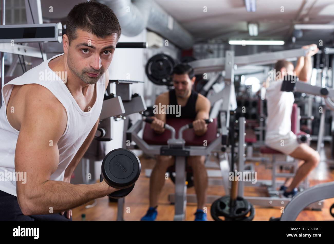 Guy during workout in gym with dumbbells Stock Photo - Alamy