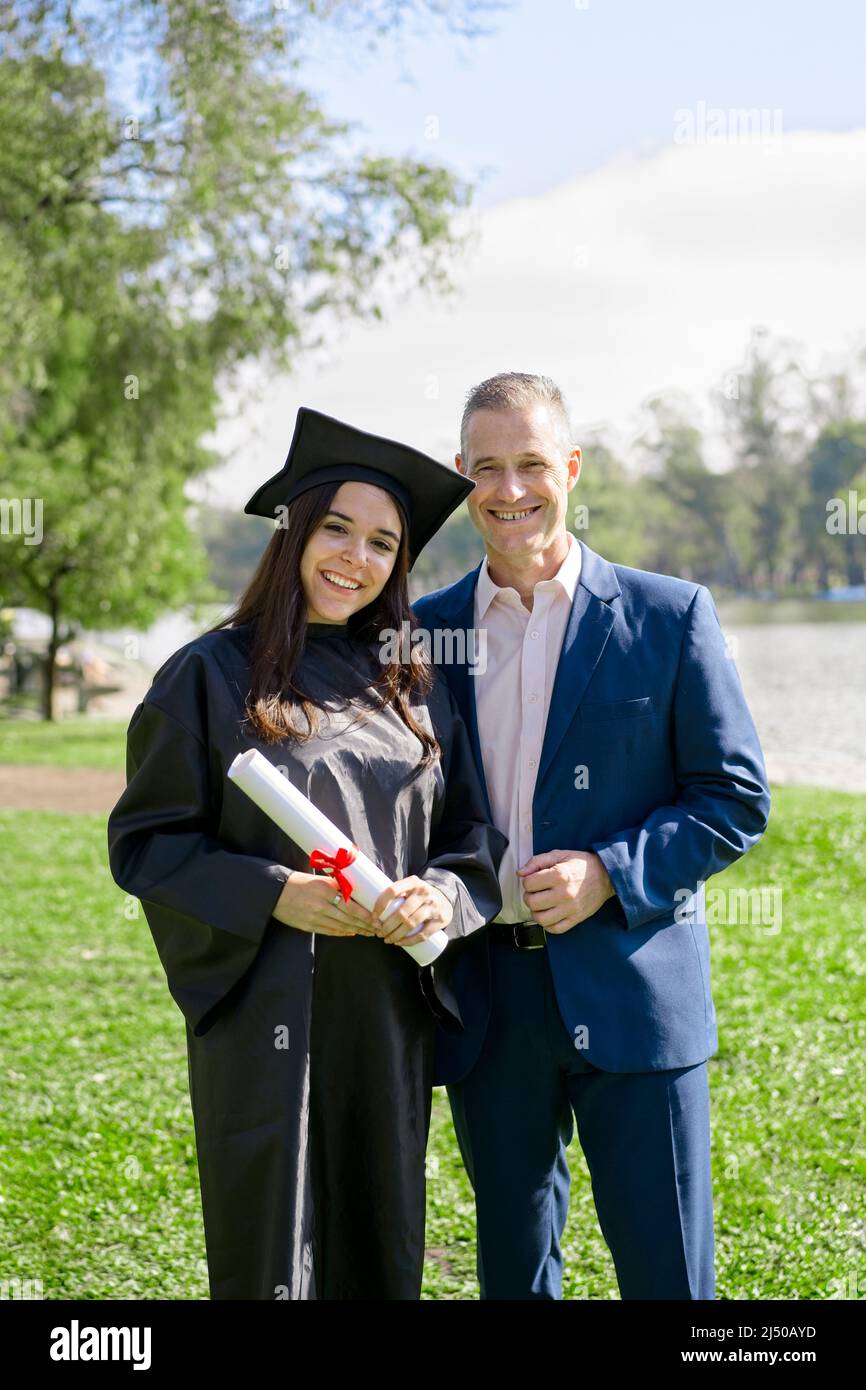 Young girl recently graduated, dressed in cap and gown, with her degree in her hands ...