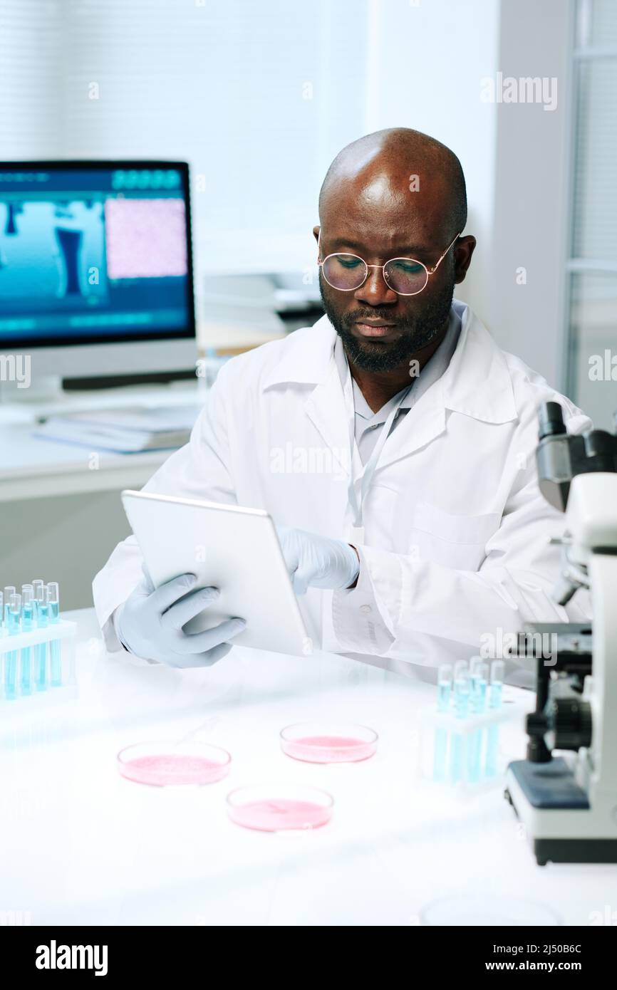 African American scientist in whitecoat, gloves and eyeglasses ...
