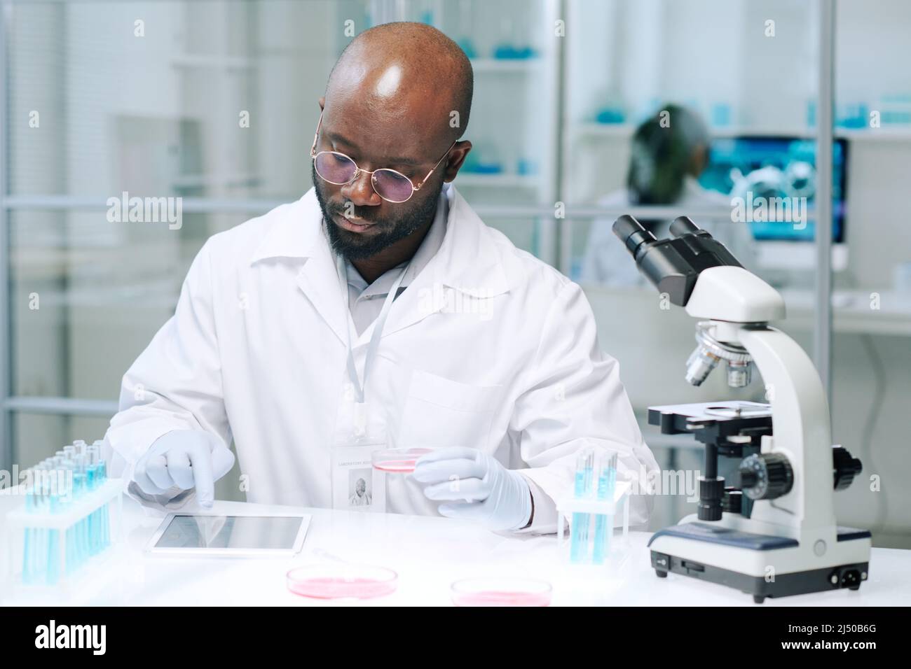 African American male scientist sitting by workplace in laboratory and ...