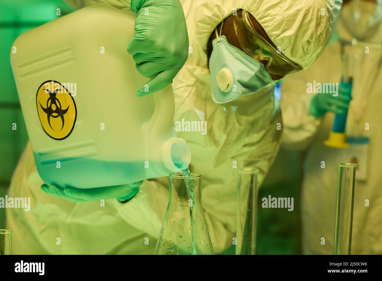 African American male chemist pouring blue liquid from plastic canister ...