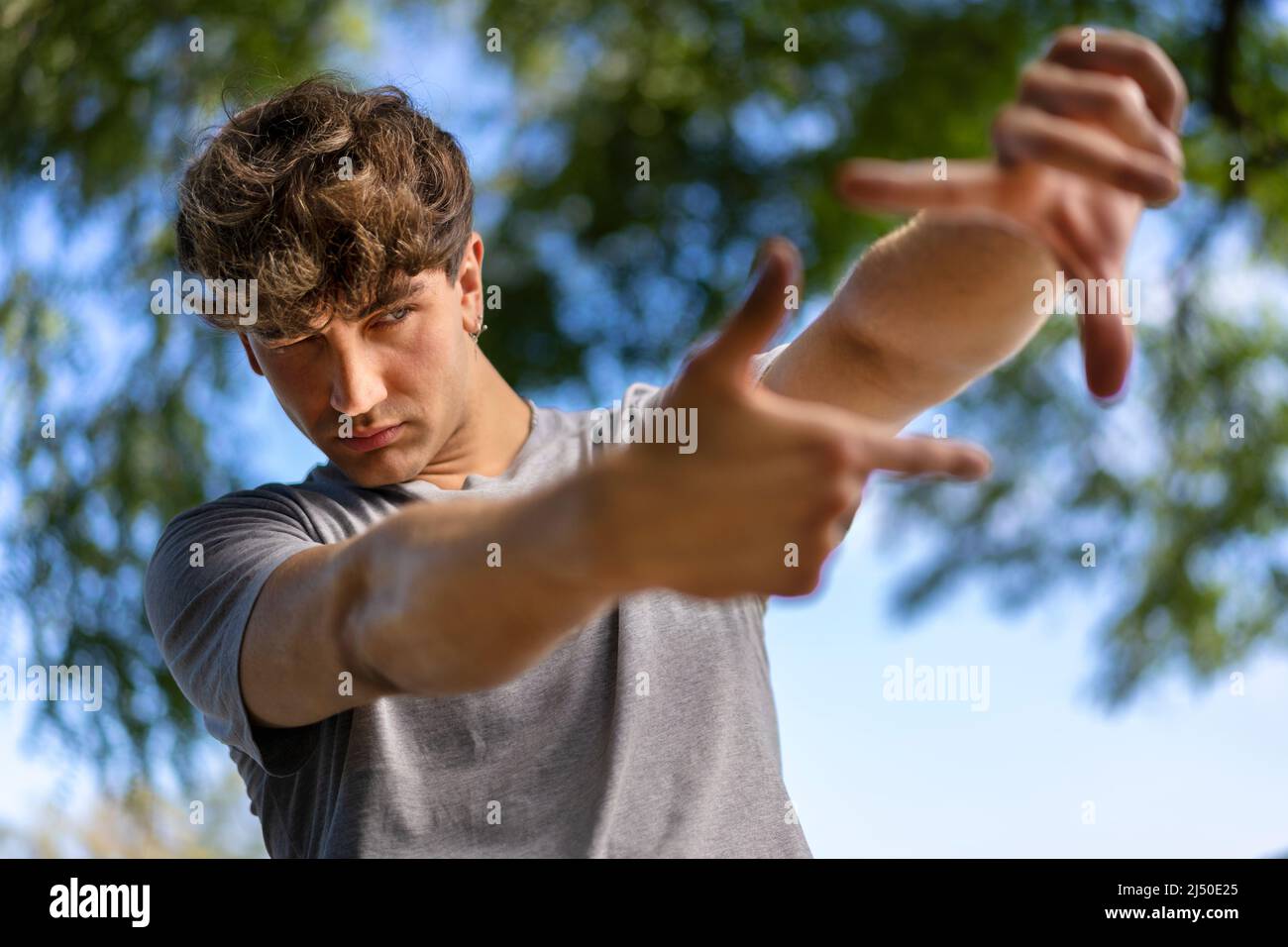 A handsome young man blinks his eyes and looks through a frame made up ...