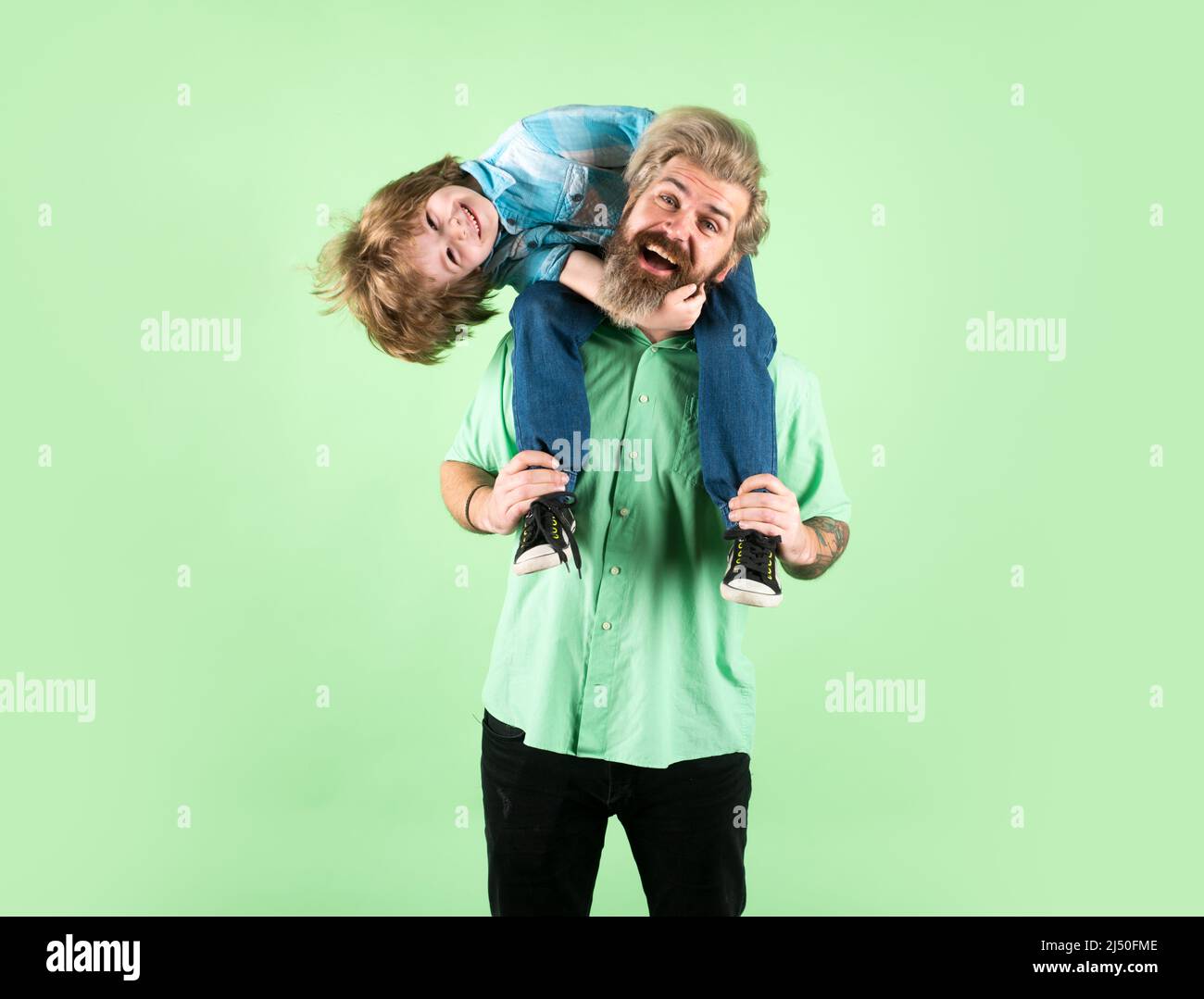 Portrait of happy father giving son piggyback ride on his shoulders ...