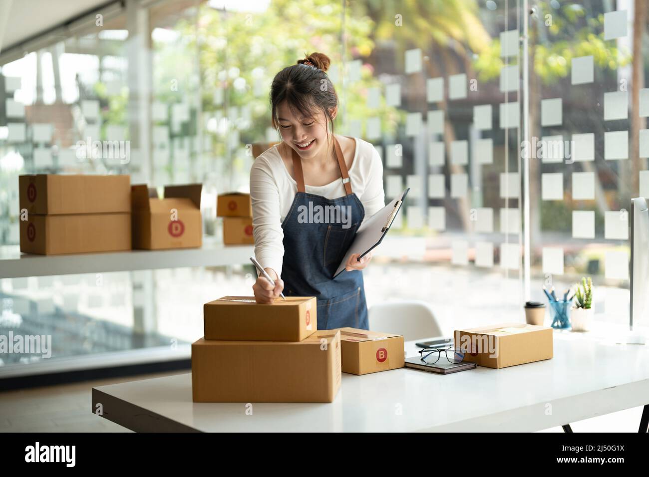 Young Asian small business owner working at home office, taking note on ...