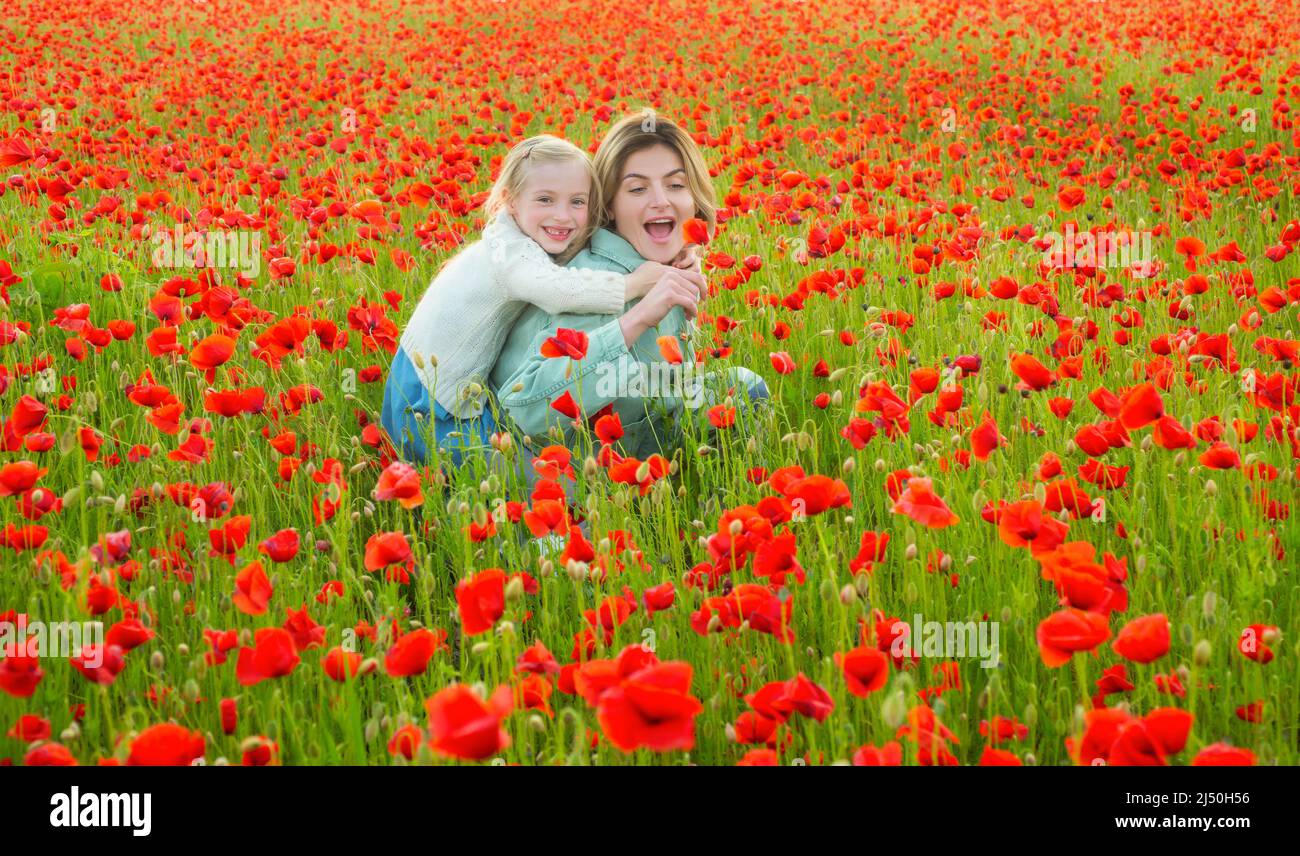 Beautiful mother and daughter in spring poppy flower field. Mom holds ...