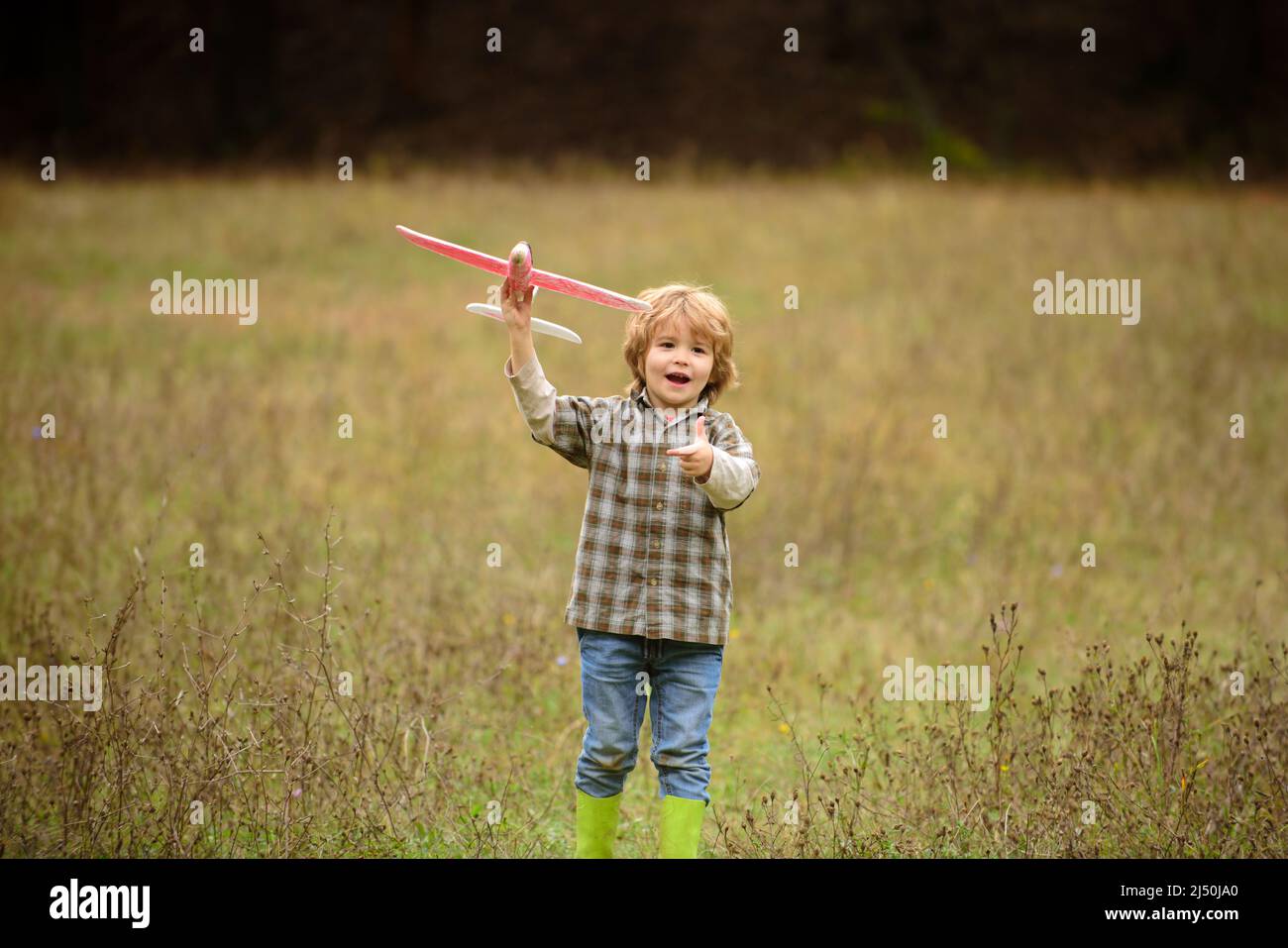Kid having fun with toy airplane in field. Little boy with wooden plane ...