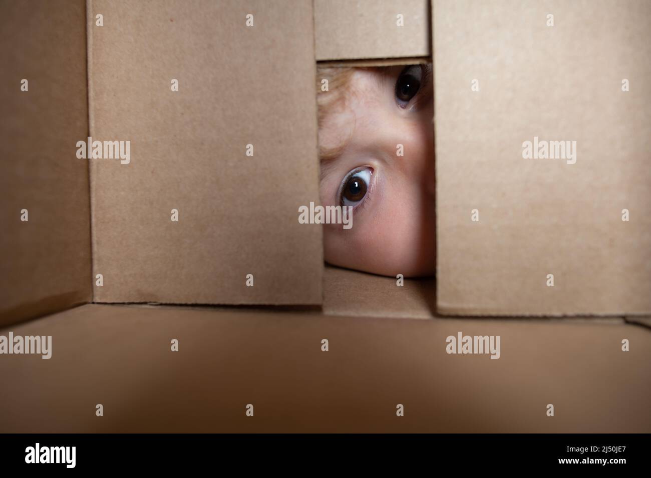 Excited child boy looking into the box, shipping cardboard box. Closeup ...