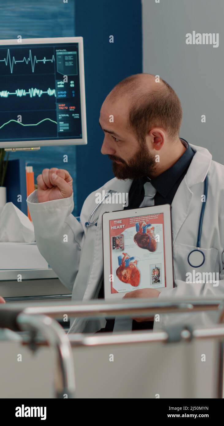 Doctor showing cardiovascular image on tablet to ill patient in ...