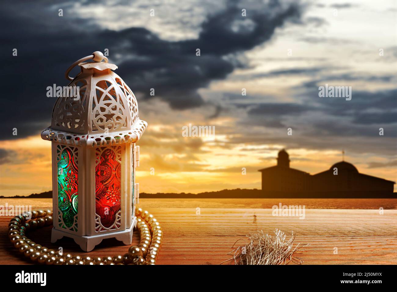 Arabic lamp with colorful light and prayer beads on a wooden table with ...