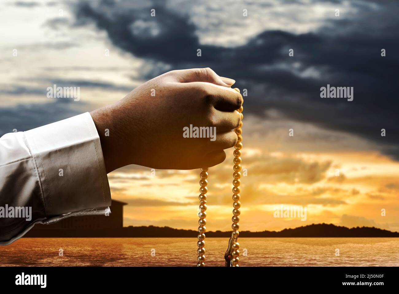 Muslim man praying with prayer beads in his hands with the dramatic ...