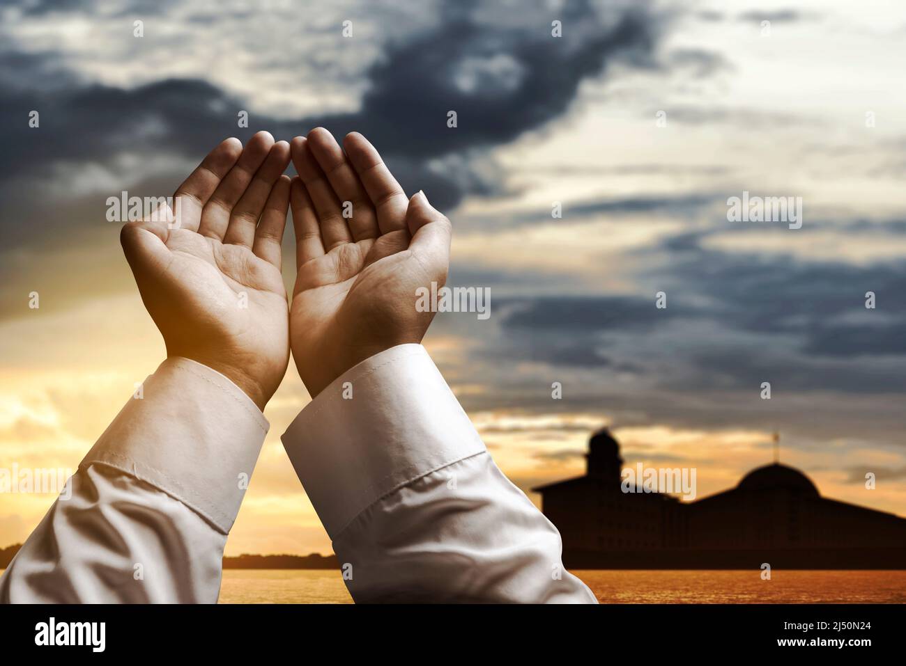 Muslim man standing while raised hands and praying with the dramatic ...