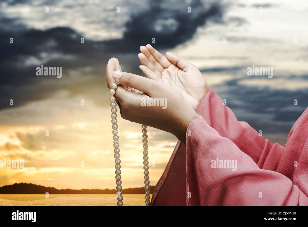 Muslim woman praying with prayer beads on her hands with the dramatic ...