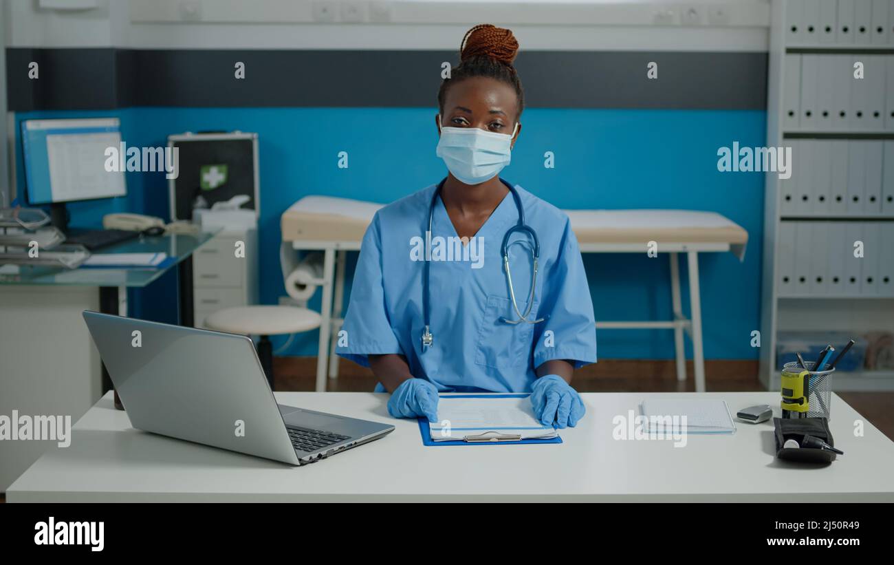 Portrait of woman working as medical assistant wearing face mask and ...