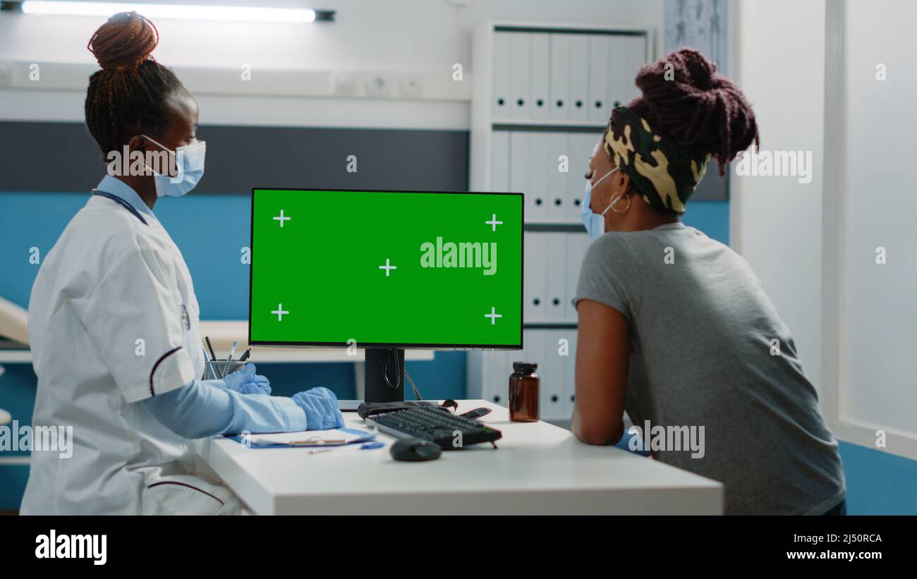 African american doctor and patient looking at green screen on computer ...