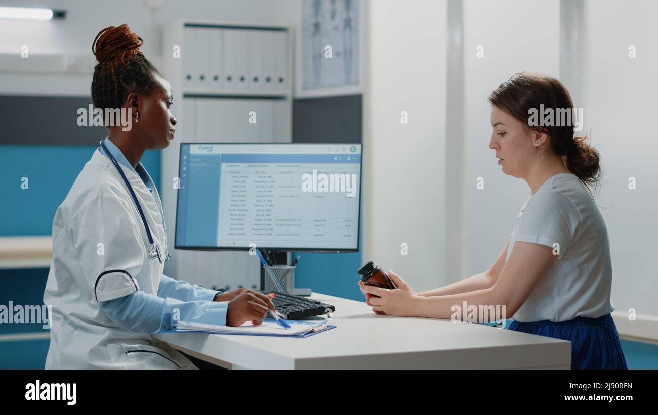 Specialist giving bottle of pills to woman for prescription treatment ...
