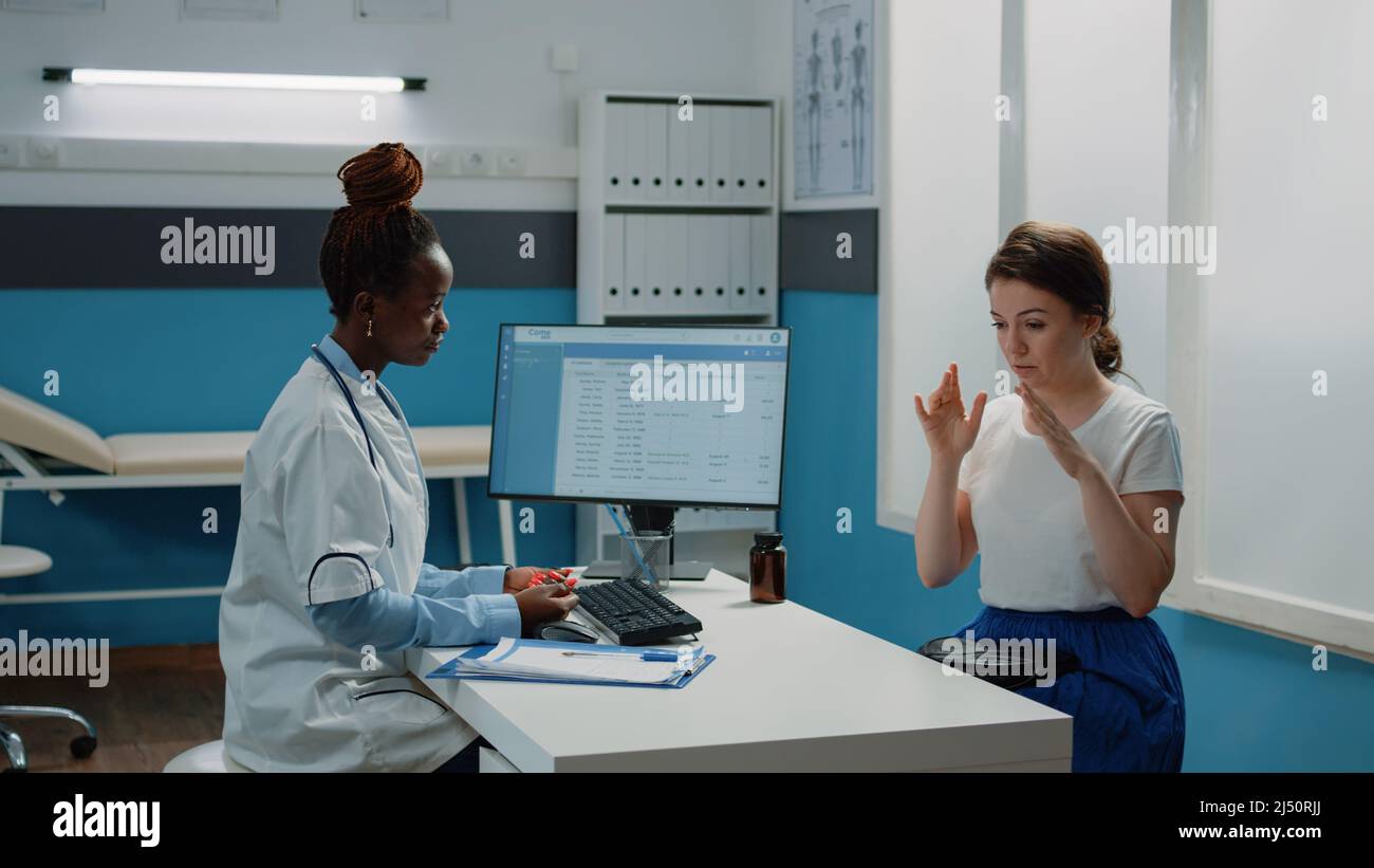 Patient explaining pain and symptoms to doctor at appointment for ...