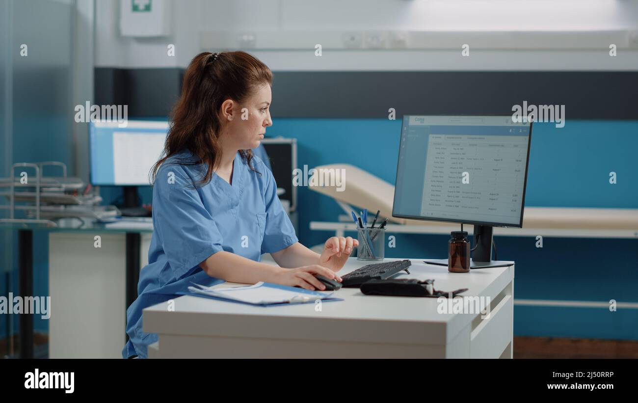 Medical assistant working on computer with patient information at desk ...