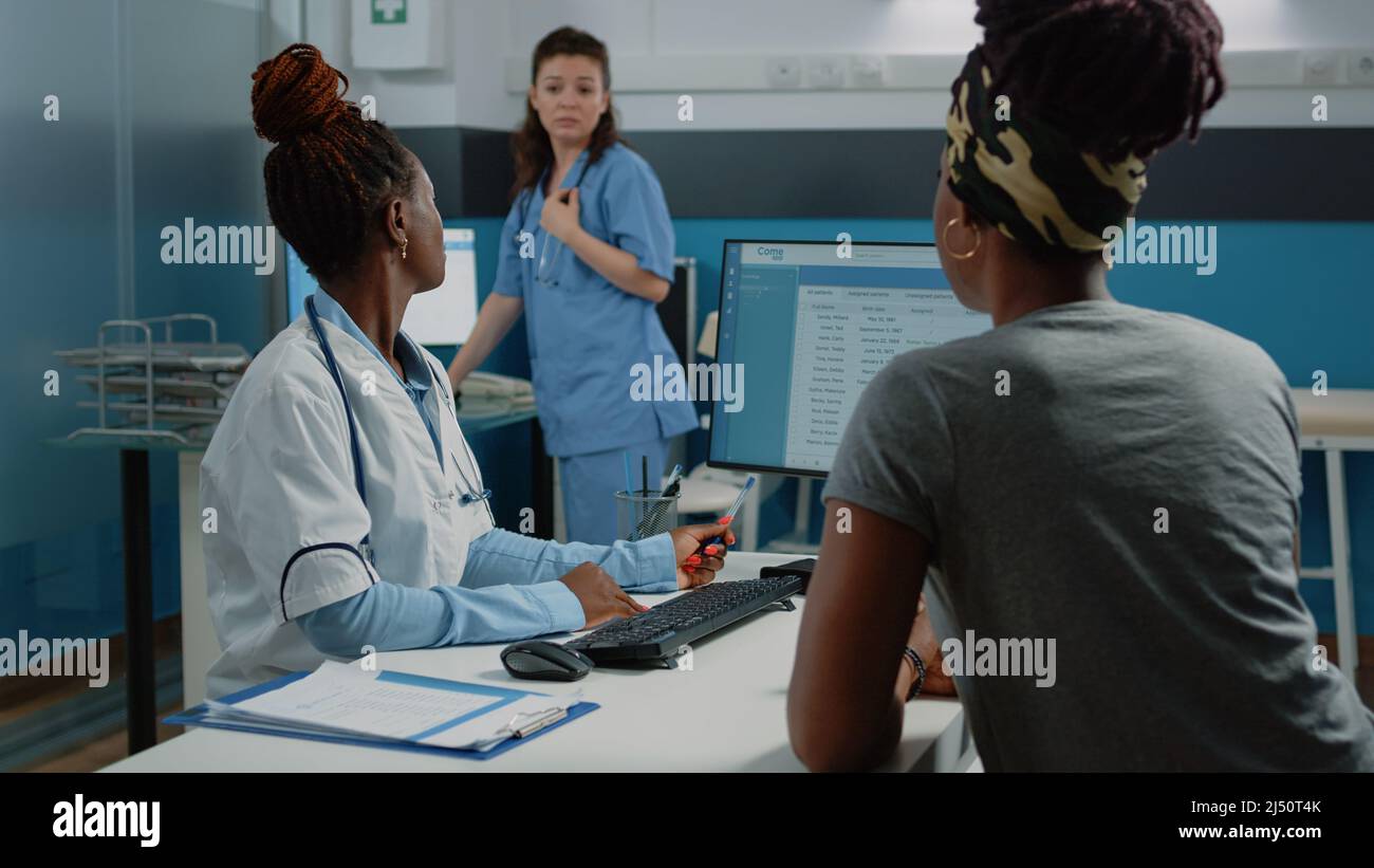 Medic explaining medical information on computer to patient while ...
