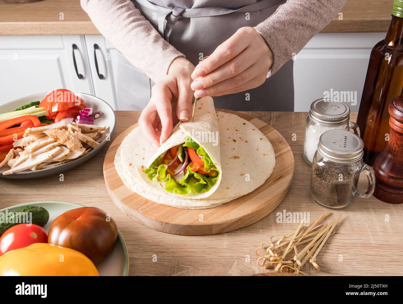 the process of wrapping a flatbread with vegetables and chicken pieces ...