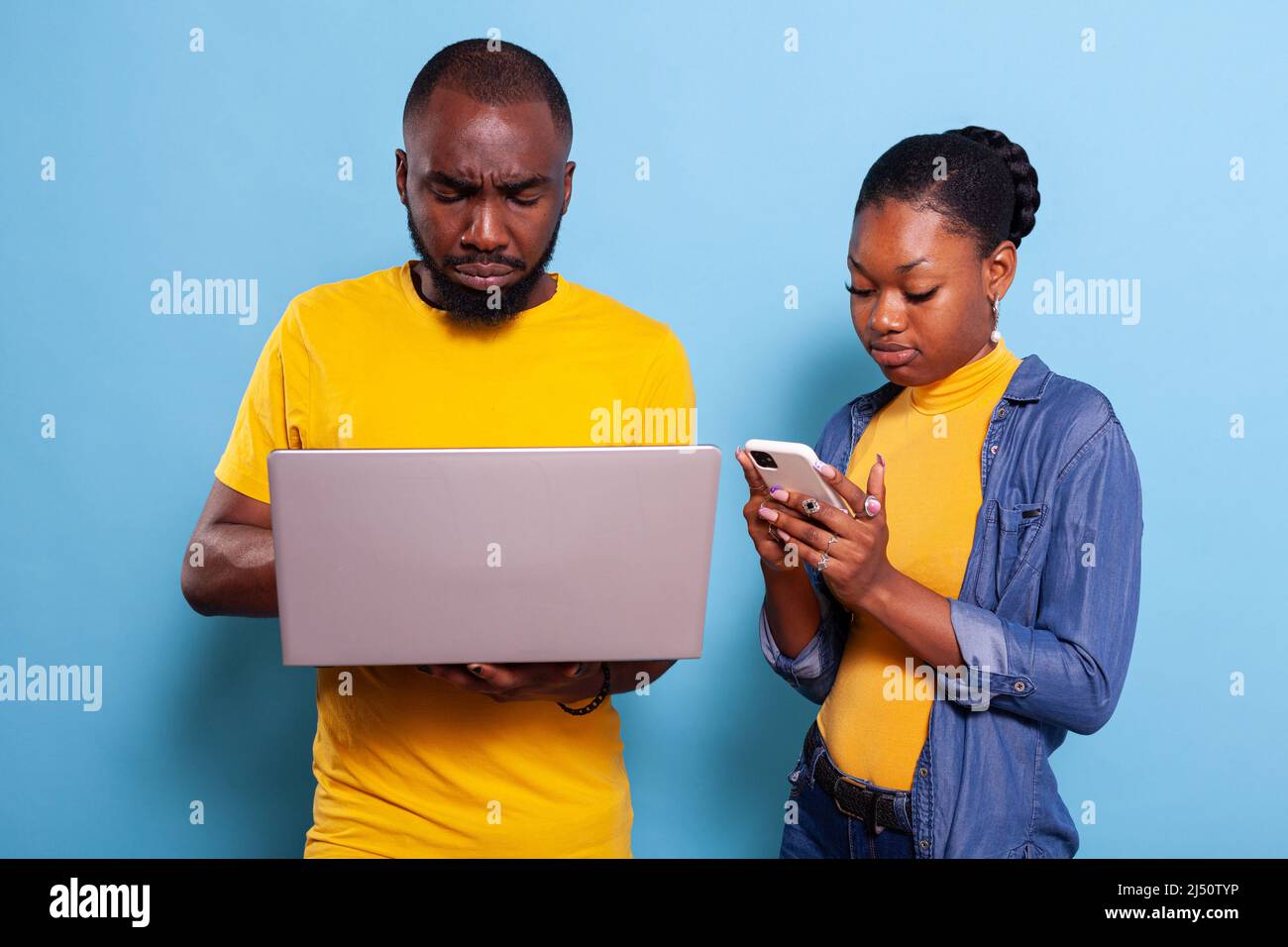 Modern couple browsing internet on laptop and smartphone, using social ...