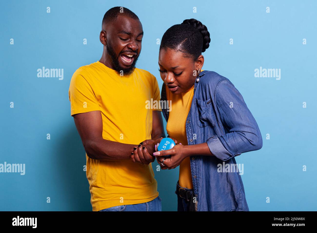 Man and woman trying to train biceps with dumbbells. Boyfriend and ...