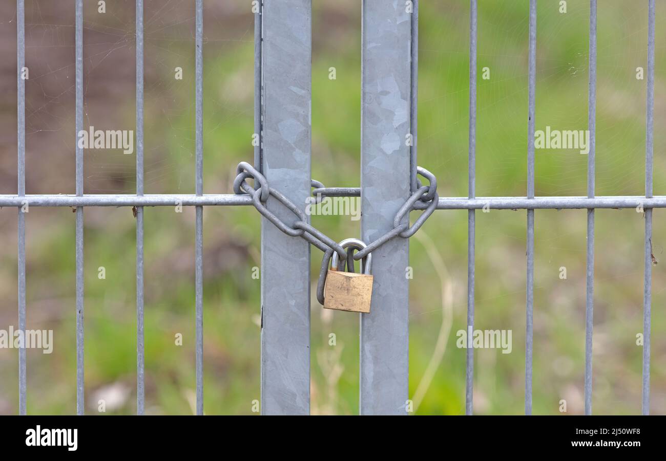 Large metal fence locked with a padlock and a chain, selective focus ...