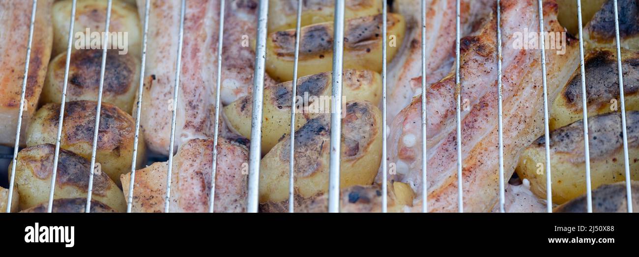 Grill potatoes and meat on wire rack closeup Stock Photo - Alamy