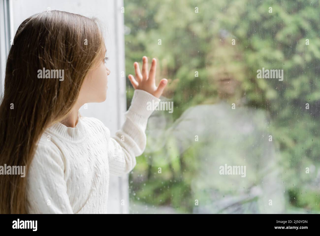 girl with long hair touching window glass with raindrops Stock Photo ...