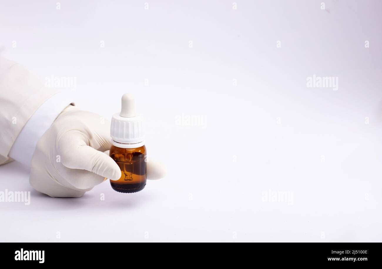 marijuana oil in drop dispenser bottle in gloved hands, white ...