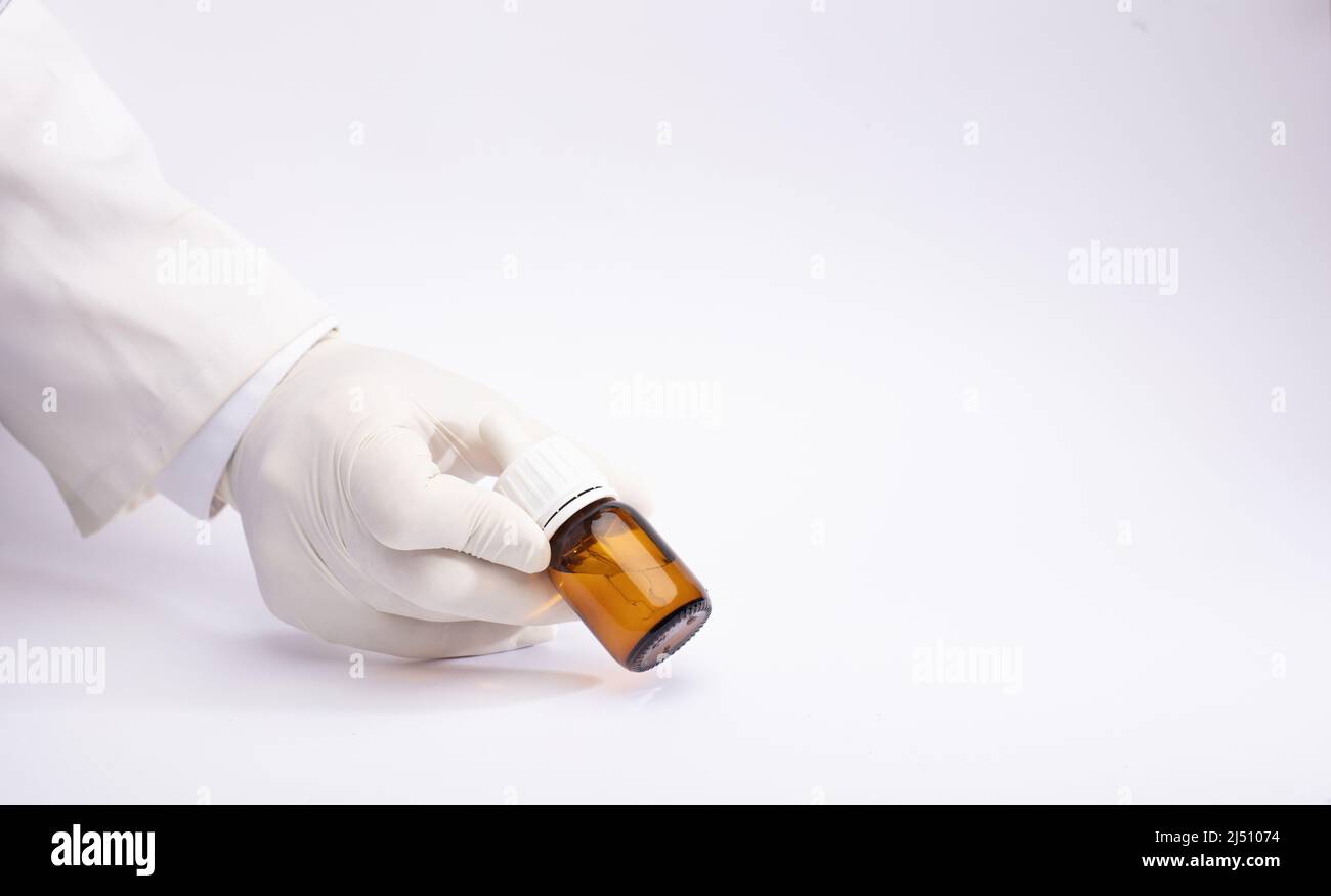 marijuana oil in drop dispenser bottle in gloved hands, white ...