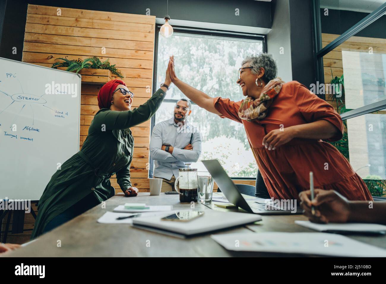 Successful businesswomen high fiving each other during an office ...